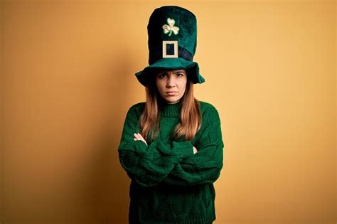 세인트 패트릭의 날 축하 에 녹색 모자를 입고 젊은 아름다운 갈색 머리 여자 회의적이고 긴장 교차 팔로 얼굴에 표정을 거부 부정적인 사람 St Patricks Day에