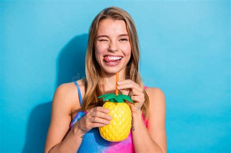 Cheerful Woman Enjoying A Tropical Drink While Posing Playfully Against A Vibrant Blue