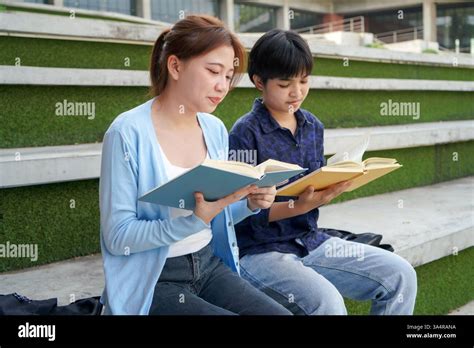 Relaxed Scene Of Two Asian College Students Seated On Modern Concrete