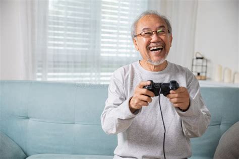 Asian Senior Old Man Enjoying Holding Joystick Playing Video Game At