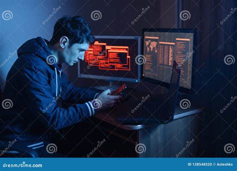 Male Hacker Holding The Phone In His Hands Trying To Hack The Mobile