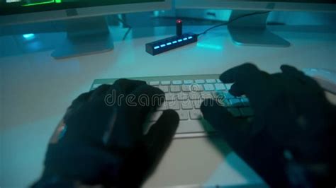 hacker stretching hands in black gloves and typing on a computer