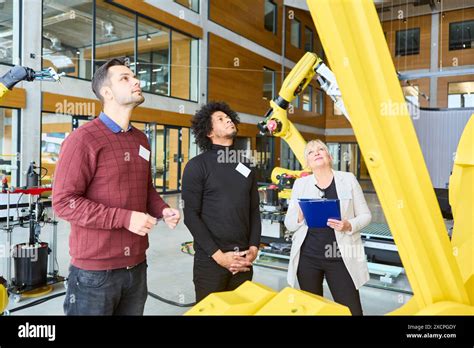 Group Of Engineers And Scientists Examining Multi Purpose Robotic Arms