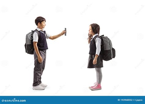 Escolar Con Uniforme De Pie Y Mostrando Un Smartphone A Una Colegiala
