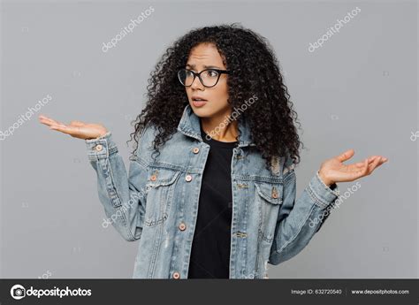 confused unaware afro woman crisp hair raises hands bewilderment looks