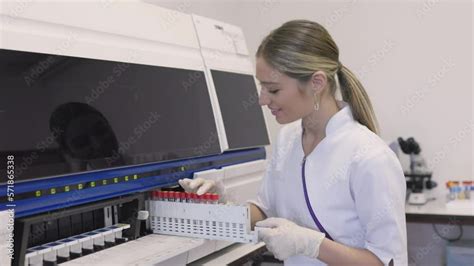 Lab Tech Loading Samples Into A Chemistry Analyzer Female Lab Tech Loading Specimen For