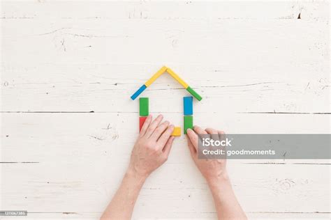 한 남자의 손이 여러 가지 색상의 나무 블록에서 집을 조립하고 있습니다 아이들의 조기 발달과 교육 아빠는 자신의 아이에게 큐브를