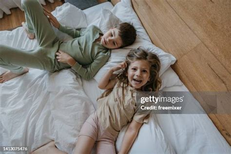 Little Brother And Sister Lying On Bed And Enjoying High Res Stock
