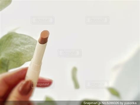 グリーンの背景にリップを持つ女性の手の写真・画像素材 Snapmart（スナップマート）