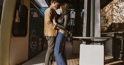 Woman In Brown Jacket And Blue Denim Jeans Standing Beside White Wall