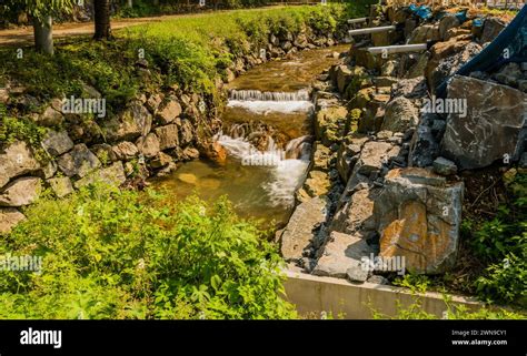 Stream Flowing Over Man Made Waterfall In Rural Farming Community In