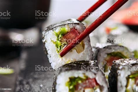 쌀 크림 치즈 추카 샐러드 토마토 오이 노리와 채식 초밥 롤의 매크로 샷 일식 레스토랑 클로즈업에서 젓가락으로 신선한 채소 롤을