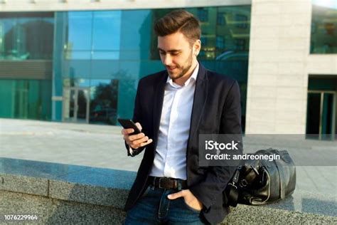 도시 전문 젊은이 스마트 휴대 전화를 사용 하 여입니다 자 켓을 입고 하는 애플 리 케이 션 문자 메시지 Sms 메시지를 사용 하 여 모바일 스마트폰 들고 사업가 거리에