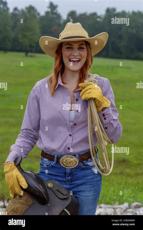 A Beautiful Redhead Model Poses In A Country Setting Wearing Cowgirl
