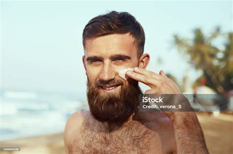 수염을 가진 잘 생긴 남자 여름에 선스크린 로션 바디와 선글라스 일광욕 남성 피트 니스 모델 태닝 건강 한 황갈색에 대 한 태양