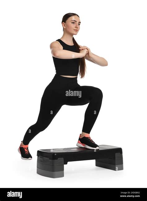 Young Woman Doing Aerobic Exercise With Step Platform On White