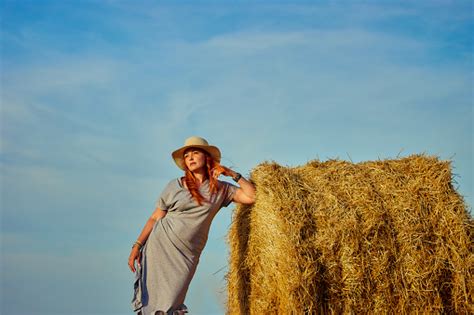 모자와 여름 드레스를 입은 아름다운 젊은 여성이 들판의 건초 뭉치에 앉아 있습니다 시골 자연 밀밭 나라의 휴식 자연과의 단결 40 44세에 대한 스톡 사진 및 기타 이미지