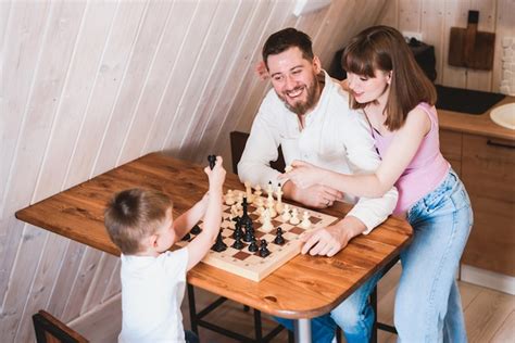 Mamá Embarazada Viendo A Papá E Hijo Jugar Al Ajedrez En La Mesa Foto