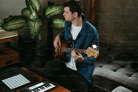 소파에 앉아 기타를 연주하는 남자 사진 Unsplash의 음악가 이미지