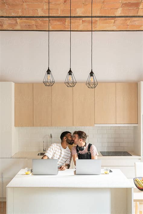 Gay Couple Kissing While Working Using Laptops By Stocksy Contributor
