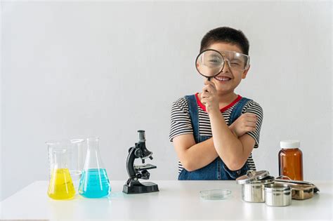 교육 과학자 개념 과학 실험실에서 뭔가를 보면서 책상에 현미경과 튜브 실험으로 그의 손 앞면 보기 눈에 돋보기를 들고 어린 아이