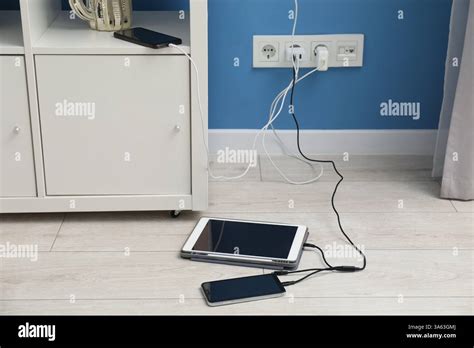 Usb Adapters With Cables Plugged Into Electric Socket Charging Different Devices Indoors Stock