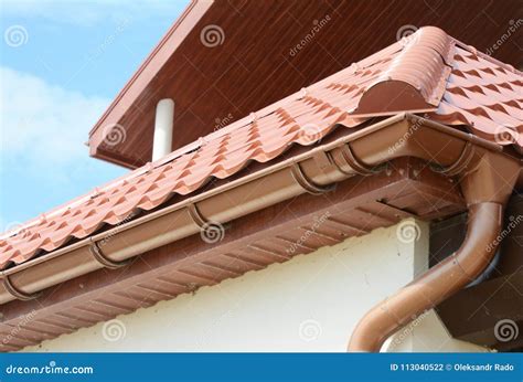 Close Up On Roof Gutter Holder And Guttering Downspout Pipe With Clay Tiles Roof Installing