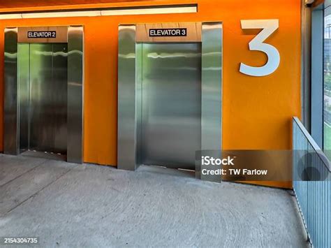 주차 경사로 차고 주황색 배경에 큰 흰색 숫자와 스테인리스 스틸 엘리베이터가 있는 주차장의 3층 0명에 대한 스톡 사진 및 기타 이미지 Istock