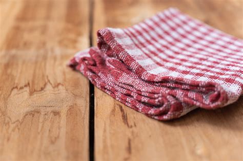 빨간 격자 무늬 주방 수건이 나무 테이블의 조리대에 놓여 있습니다 거친 보드에 구겨진 수건이나 주방 냅킨 클로즈업 선택적 초점