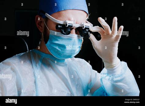 Surgeon Wearing Binocular Magnifying Glasses Operates On A Patient In A