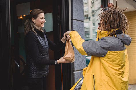 레스토랑 앞에서 소포를 집어 들고 공포에 질린 젊은 배달남자 20 24세에 대한 스톡 사진 및 기타 이미지 20 24세 2명 Brand Name Smart Phone
