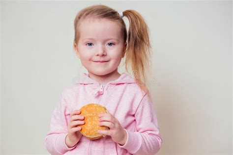 Little Blonde Girl Is Eating Baked Vegetarian Burger With Vegetables
