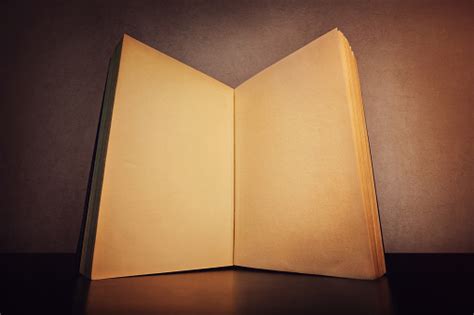 테이블에 있는 열린 책을 황금색 빈 페이지로 닫습니다 빈 시트 복사 공간 오래된 교과서 또는 노트북 어두운 회색 배경에 고립 된