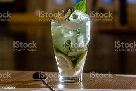오이는 유리에 해독수를 주입했습니다 수제 맛 레모네이드 나무 테이블에 있는 유리잔에 바질과 레몬을 곁들인 신선한 오이 물 감귤류
