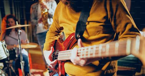 의자에 앉아 기타를 연주하는 베이스 기타리스트의 클로즈업 배경 색소폰 연주자와 피아노 연주자 홈 스튜디오 인테리어 사진 Unsplash의 성인 전용 이미지