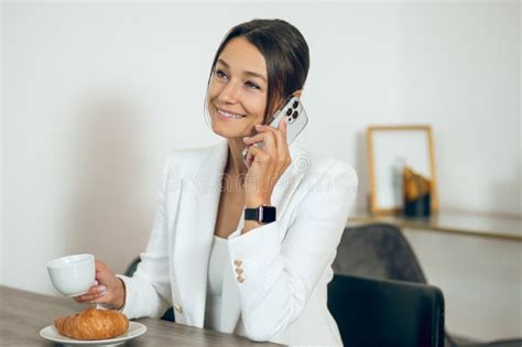 Dark Haired Business Woman In White Jacket Having Morning Coffee And