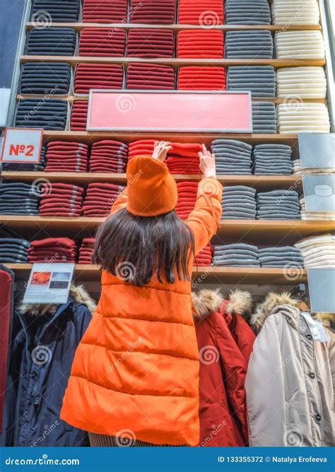 The Girl Holds Out Her Hand For Clothes On The Store Shelf Shopper