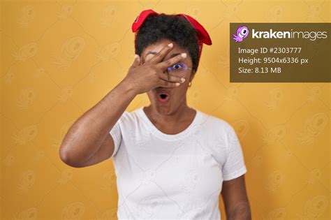 Young African American Woman Standing Over Yellow Background Peeking In