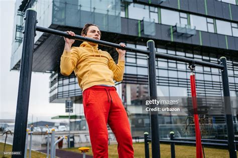 Young Man Doing Pullups On A Bar Outdoors In The Rain High Res Stock