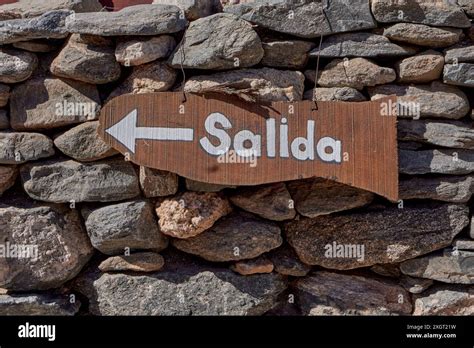Wooden Exit Sign With A Directional Arrow On A Rustic Stone Wall Stock