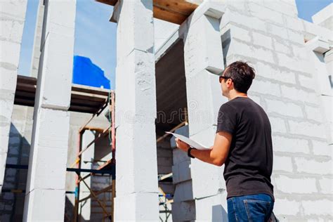 Man Architect Engineer Checking House Under Construction Comparing With