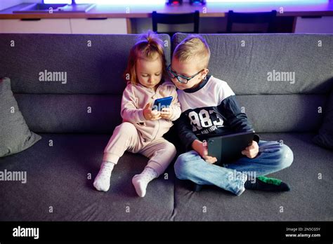 Danya And His Sister Emilia Play With Mobile Phones And Tablets Stock