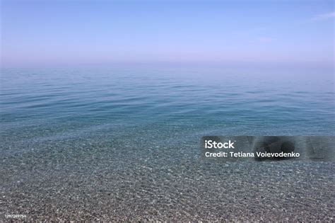 화창한 여름날 평온한 바다의 파노라마 조약돌 해변의 맑은 바다 수 화창한 여름날 수평선에 부드러운 분홍색 안개가 있는 밝은 푸른 하늘 0명에 대한 스톡 사진 및 기타 이미지