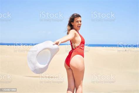 Maspalomas 모래 언덕 Bech에서 여름 스윈 수트를 입고 열린 팔로 일광욕하는 젊은 아름다운 여성 갈색 머리에 대한