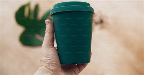 일회용 플라스틱을 금지합니다 나무 배경에 에코 재사용 가능한 커피 컵을 들고 있습니다 대나무 섬유로 만든 커피 컵 제로 폐기물 개념 컵에 커피를 가져 가십시오 지속