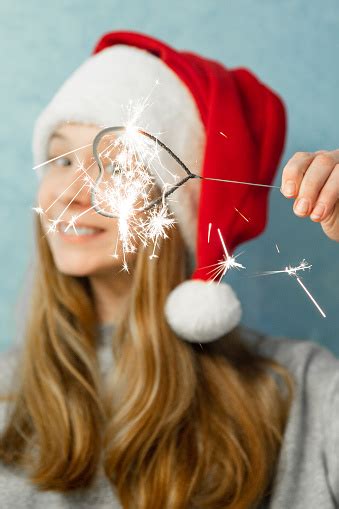 집의 회색 배경에 새해 모자에 긴 빨간 머리를 가진 아름 다운 소녀의 손에 하트 모양의 벵골 불 12월에 대한 스톡 사진 및 기타 이미지 Istock