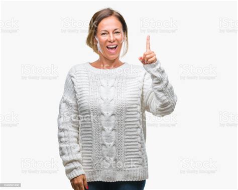 중 년 수석 히스패닉 여자 성공적인 아이디어를 고립 된 배경 가리키는 손가락에 겨울 스웨터를 입고 종료 하 고 행복 번호