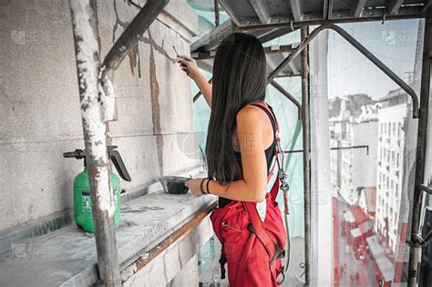 女建筑泥工在脚手架上，抹灰和翻新建筑