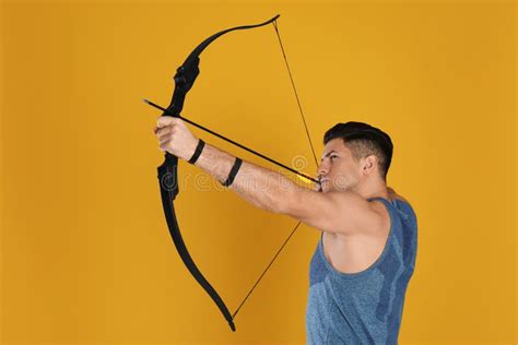 Man With Bow And Arrow Practicing Archery On Yellow Background Stock Photo Image Of Focused