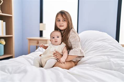 Brother And Sister Hugging Each Other Sitting Together On Bed At